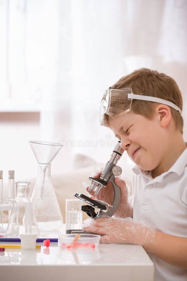 Cute Elementary Schoolboy Looking into Microscope at His Desk at Home ...