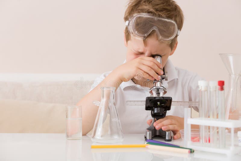 Cute Elementary Schoolboy Looking into Microscope at His Desk at Home ...