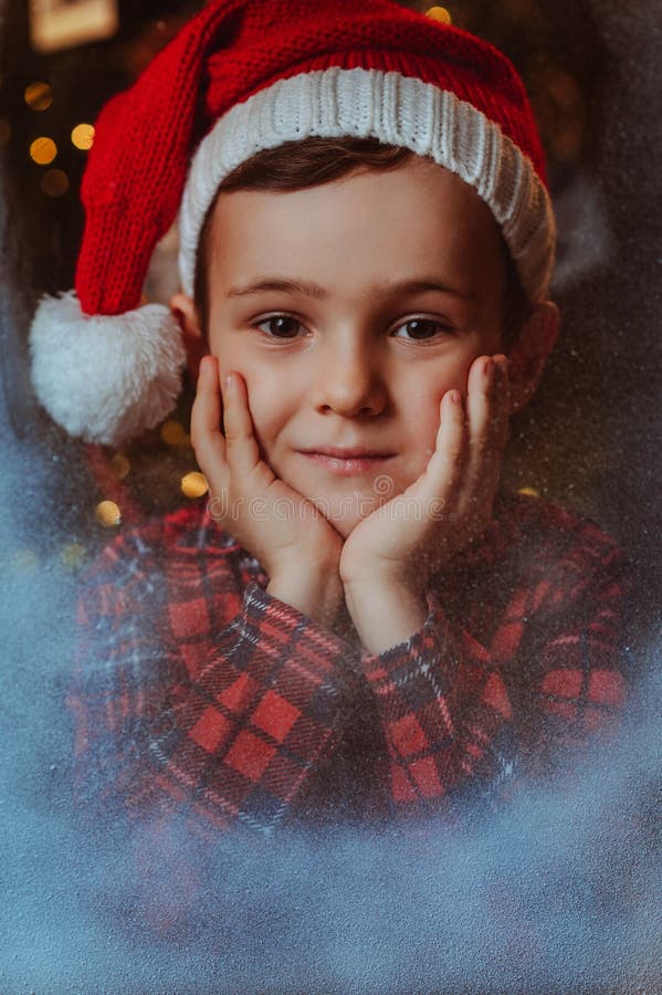 A Cute Elf Boy is Looking through a Snow-covered Window. Stock Image ...