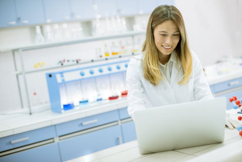 Female Researcher in White Lab Coat Using Laptop while Working in the ...