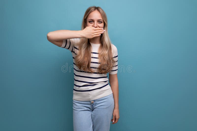 Cute Girl In Casual Clothes Covered Her Mouth With Her Hand On A Blue Isolated Background Stock