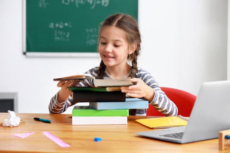 Cute Girl with Stack of Books Sitting in Classroom Stock Photo - Image ...