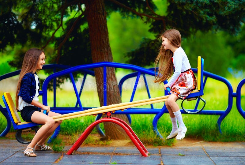 Cute Girls Having Fun On Seesaw At Playground Stock Photo - Image: 60952690