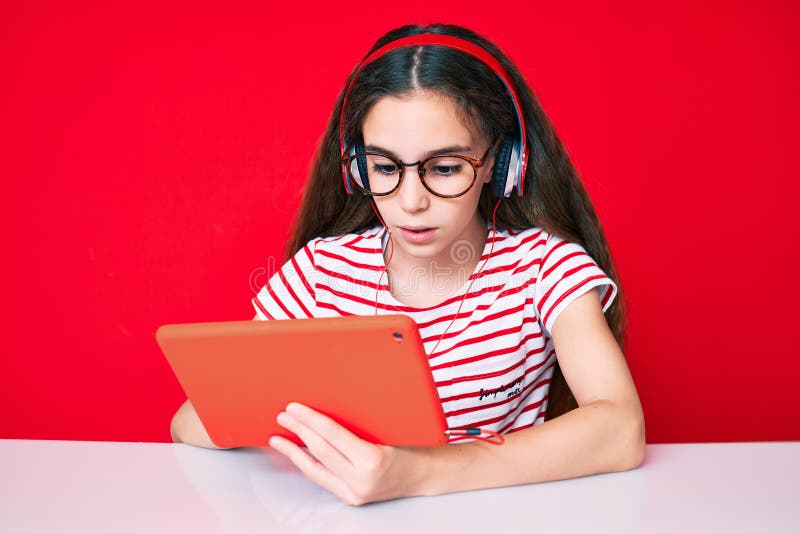 Cute Hispanic Child Girl Using Touchpad and Headphones Sitting on the ...
