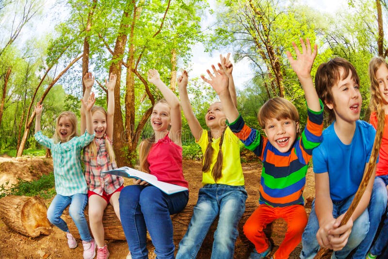 Cute Kids Sitting on the Log with Their Hands Up Stock Photo - Image of ...