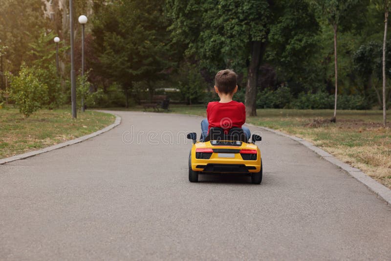 Cute Little Boy Driving Children`s Car Outdoors, Back View. Space for ...