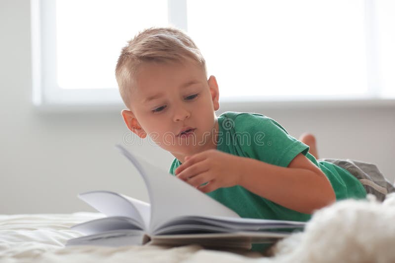 Cute Little Boy Reading Book on Bed at Home Stock Image - Image of ...