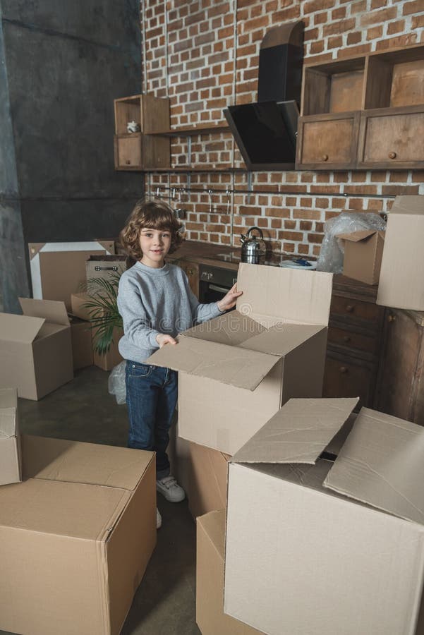 Cute Little Boy Smiling at Camera while Packing Boxes Stock Photo ...