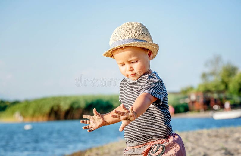 A Cute Little Boy with Summer Hat Playing in the Sand on the Bea Stock ...