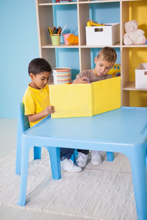 Cute Little Boys Reading at Desk in Classroom Stock Image - Image of ...