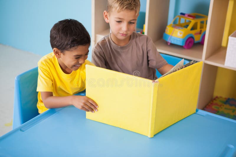 Cute Little Boys Reading at Desk in Classroom Stock Photo - Image of ...