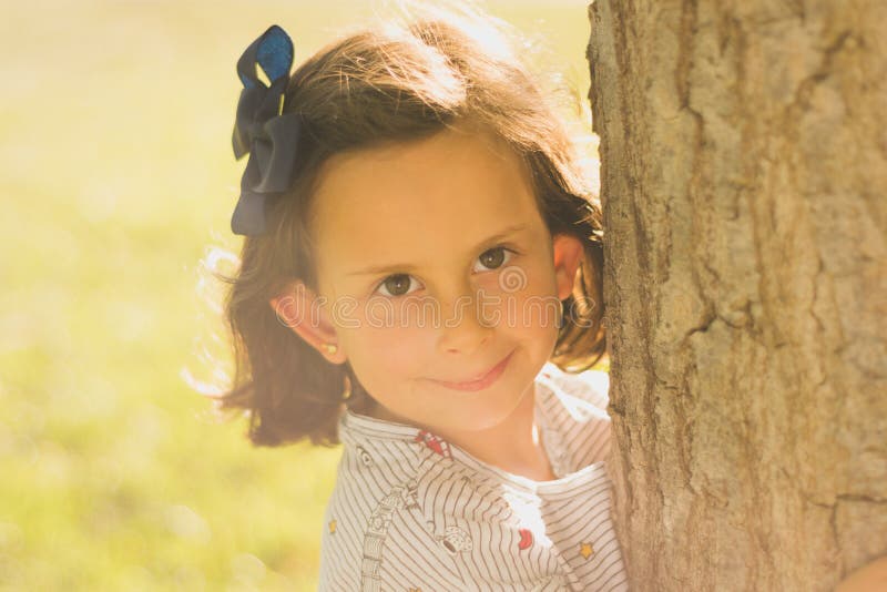 Cute Little Child Standing by the Trunk of a Tree in a Park Stock Image ...