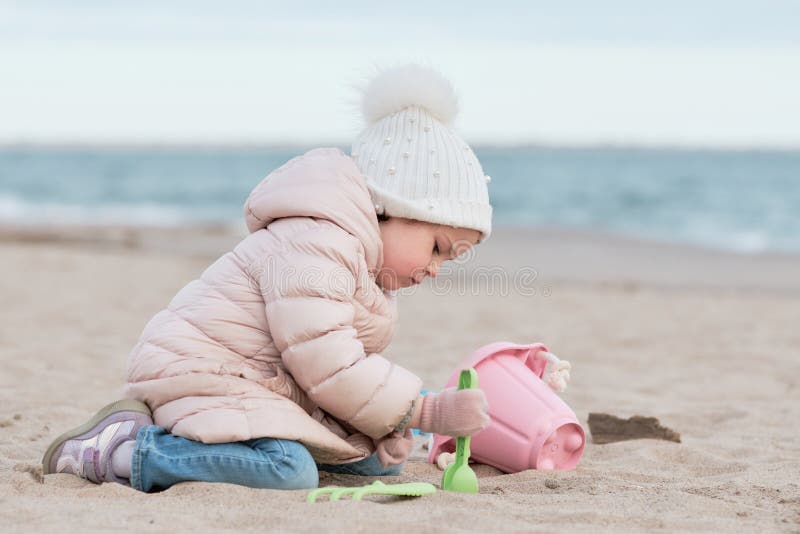 Cute Little Girl is Digging in the Sand on a Cold Day at the Beach ...