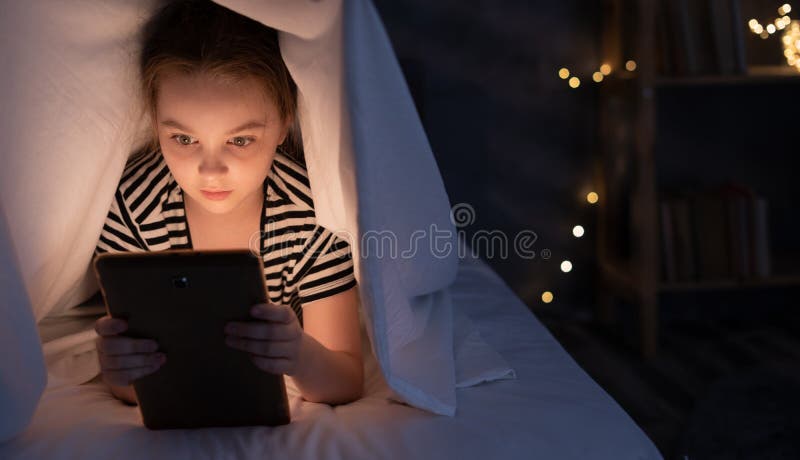 Cute Little Girl Lying Under Blanket with Tablet Computer Stock Photo ...