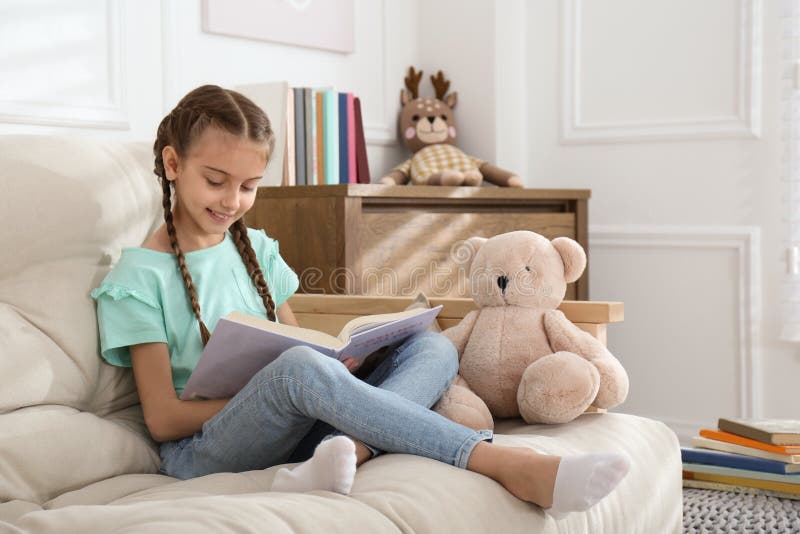Cute Little Girl Reading Book on Sofa at Home Stock Photo - Image of ...