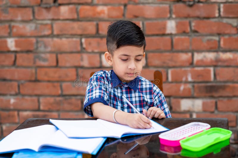 Cute Little Male Student in School Uniform Writing on Notebook while ...