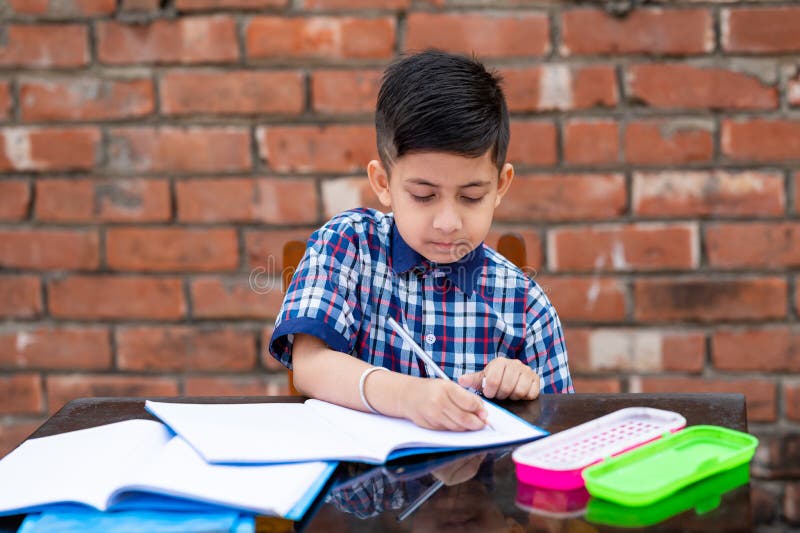 Cute Little Male Student in School Uniform Writing on Notebook while ...