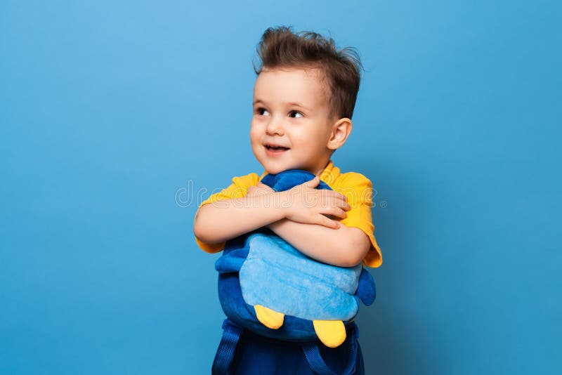 Cute Little One Cuddles with His Backpack on a Blue Background. Funny ...