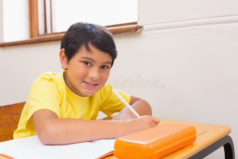 Cute Pupil Writing at Desk in Classroom Stock Photo - Image of male ...