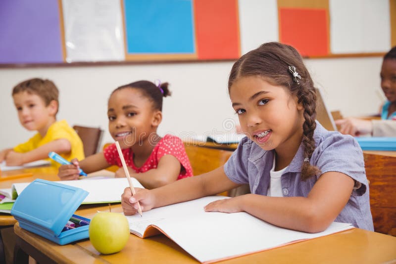 Cute Pupils Writing at Desk in Classroom Stock Image - Image of ...