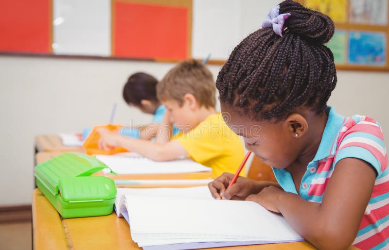 Cute Pupils Writing at Desk in Classroom Stock Image - Image of ...