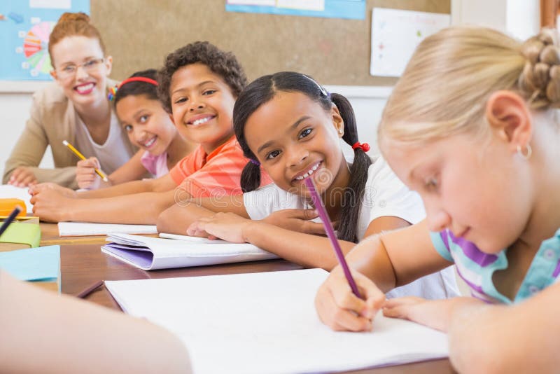 Cute Pupils Writing at Desk in Classroom Stock Image - Image of ...