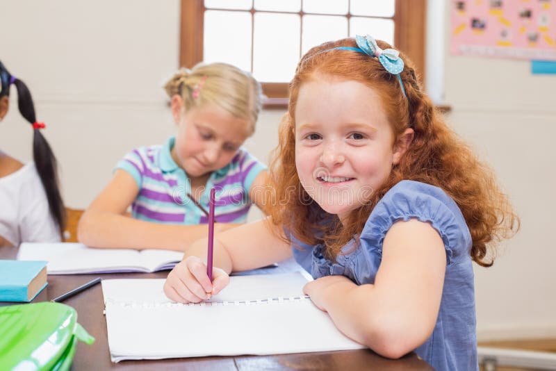 Cute Pupils Writing at Desk in Classroom Stock Photo - Image of ...