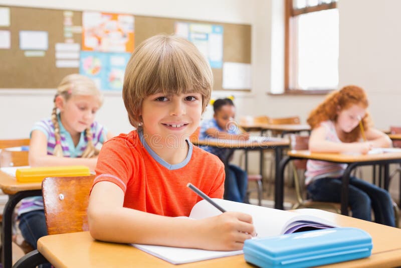 Cute Pupils Writing at Desk in Classroom Stock Image - Image of girl ...