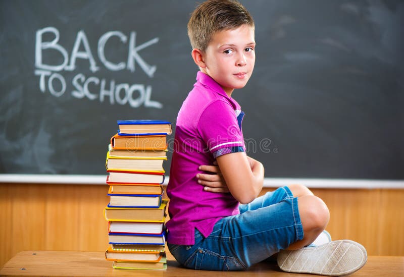 Cute School Boy Sitting with Books in Classroom Stock Photo - Image of ...