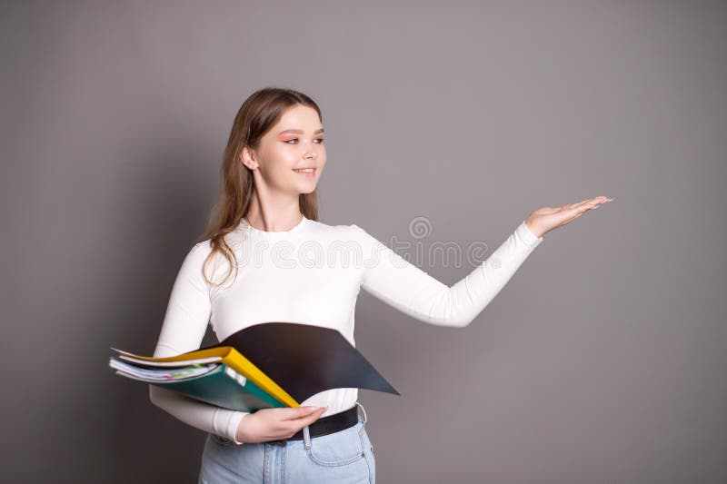 A Cute Student Girl Holds Notebooks for Notes and Points To the Side ...