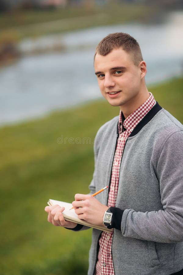 A Cute Student Writes Down His Thoughts in His Notebook Using a Pencil ...
