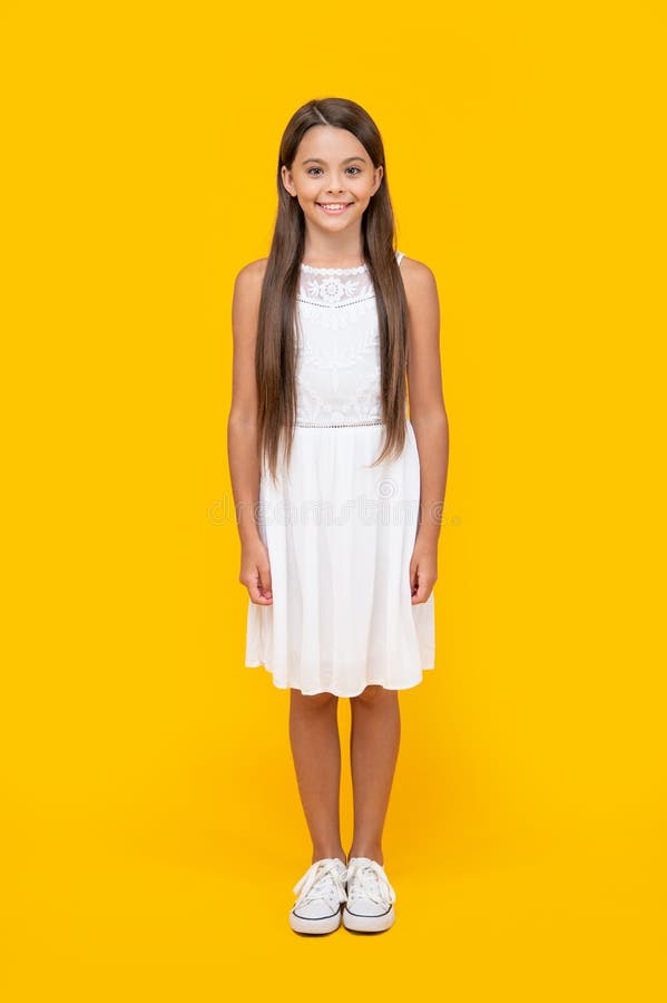 Cute Teen Girl In White Dress Standing On Yellow Background Stock Image