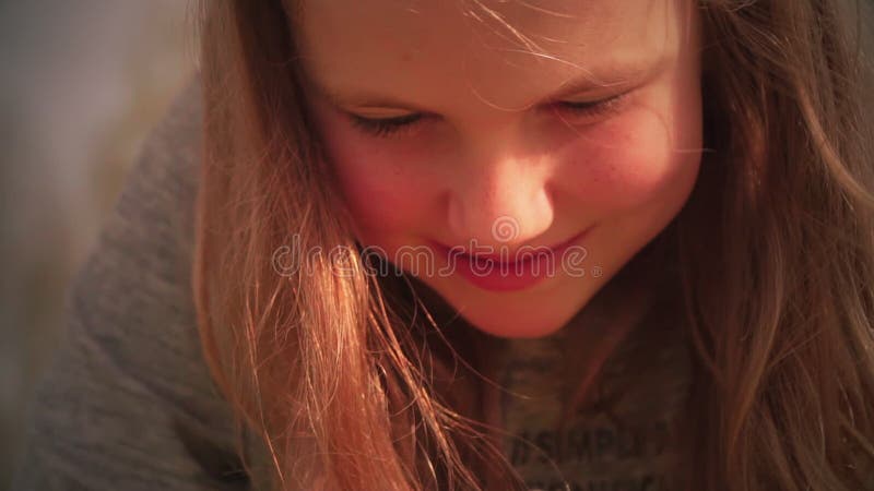 The Cute Teenage Girl Sitting On The Grass In The Park And Holding A