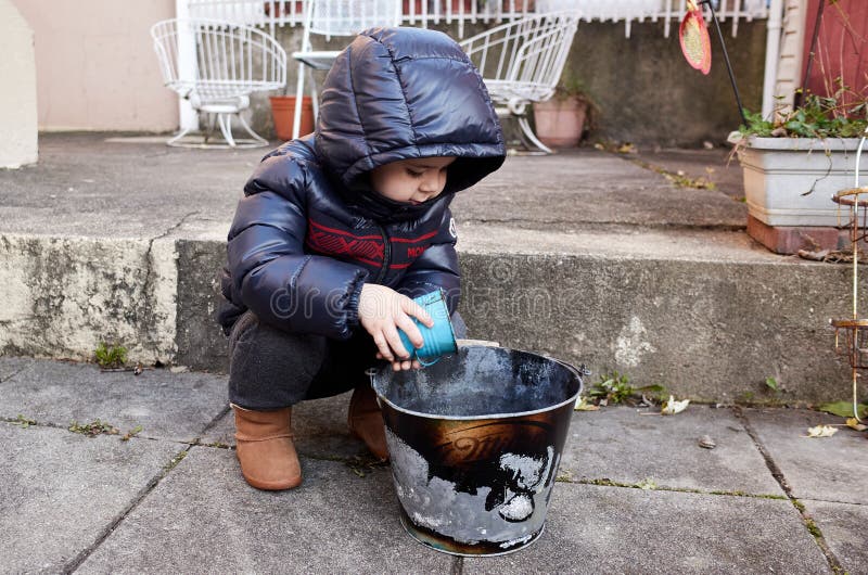 Cute Toddler Boy in a Winter Suit Playing with a Bucket in the Backyard ...