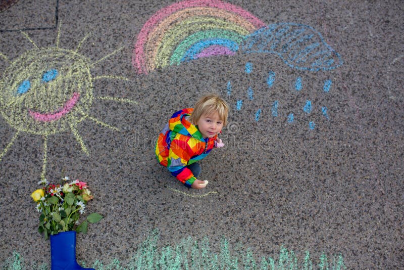 Cute Toddler. Playing in the Rain with Chalks, Drawing on the Asphalt ...