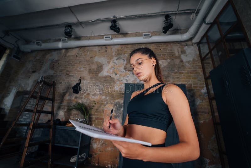 Young Women Standing Writing Down Something into the Notebook. Stock ...
