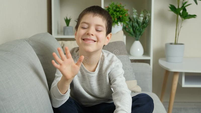 Cute 6 Year Old Boy Waving His Hand Hello or Bye while Sitting on the ...