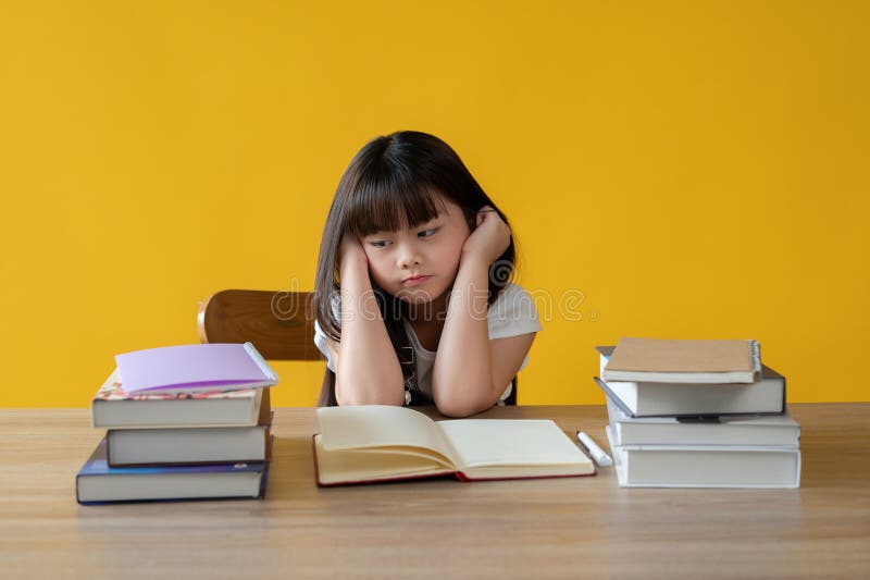 A Cute Young Asian Girl Sitting at Her Study Table with a Bored Face ...