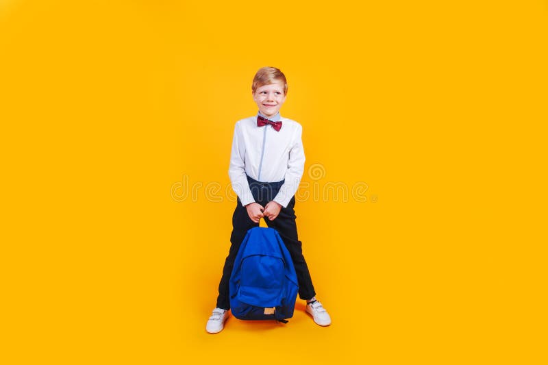 Cute Young Boy Holding Backpackand Looking Up on Yellow Studio ...
