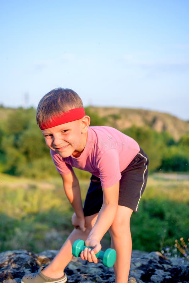 Cute Young Boy Lifting Dumbbell on Top of Boulder Stock Image - Image ...