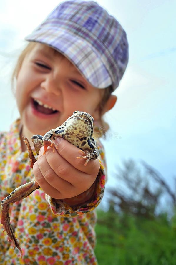 A Cute Young Child Girl Holding a Frog Toad in Hands and Laughing Stock ...