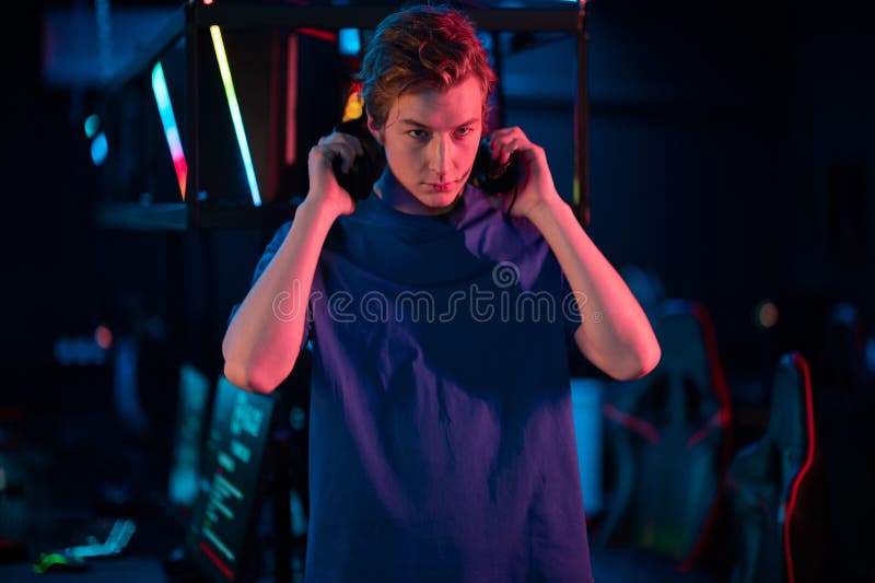 A Cute Young Gamer Guy Puts a Headset on His Head in the Computer Room ...