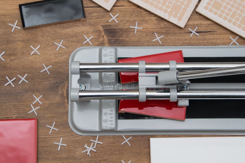 On the Cutter is a Red Tile Cut in Two, on a Wooden Surface Surrounded ...