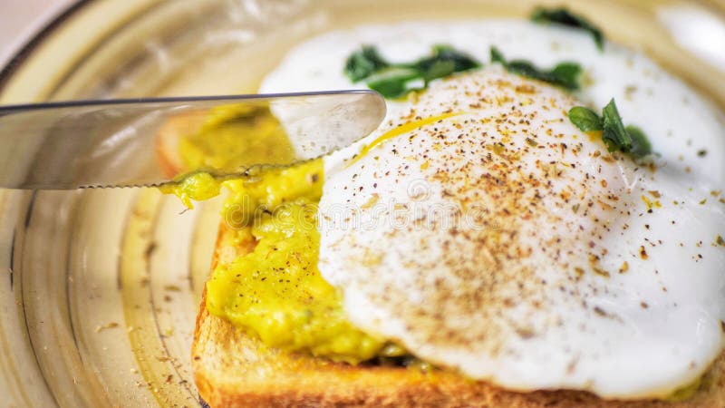 Cutting Poached Egg with Runny Egg Yolk Over Bread Toast with Mashed Avocado Spread Stock Image ...