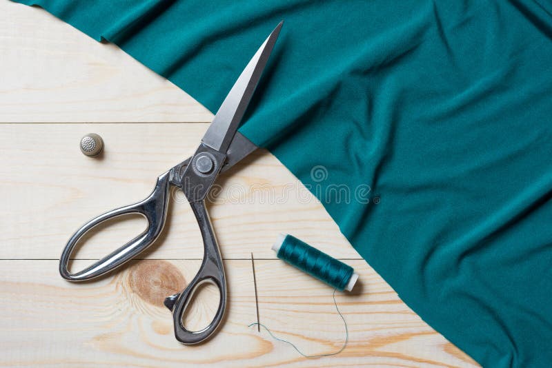 Cutting Turquoise Fabric with a Taylor Scissors on Wooden Table Stock ...