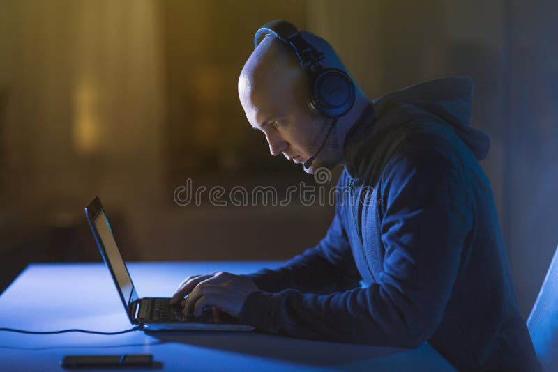 Hacker in Headset Typing on Laptop in Dark Room Stock Photo - Image of ...