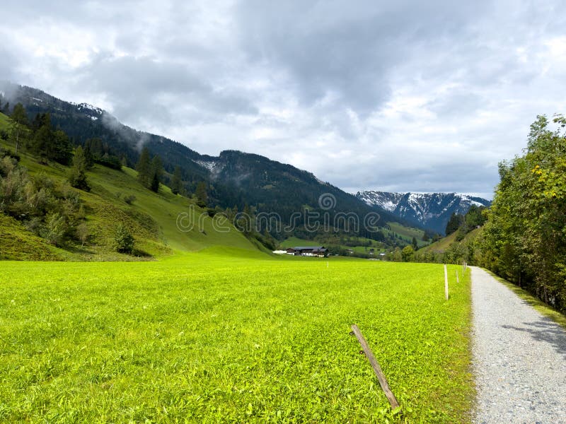 Cycle Path Along Alpine Meadow Stock Photo - Image of meadows, clouds ...
