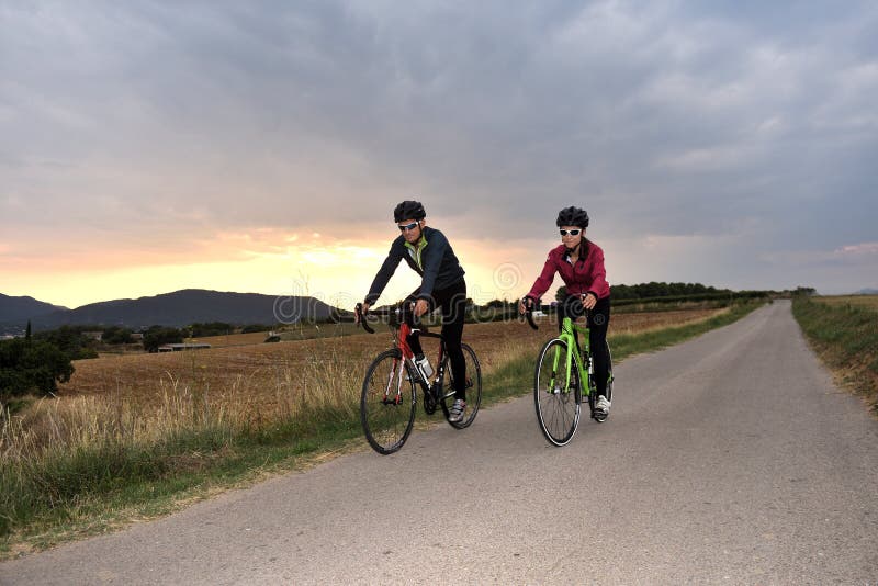 Cycling couple on a road stock photo. Image of afternoon - 125677196