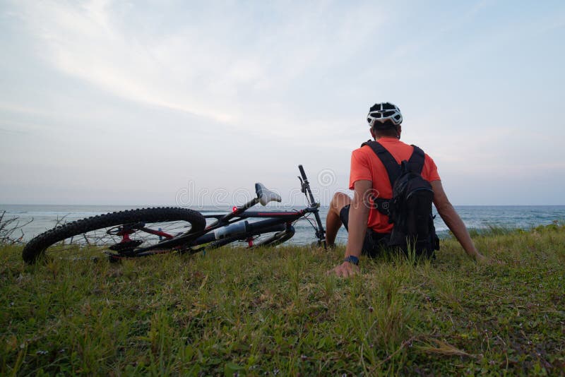 The Cyclist with Backpack, Enjoys the View of the Ocean, Sits on the ...