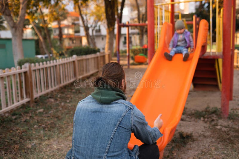 Dad and Child are Playing on the Playground. Swing and Slide Rides ...